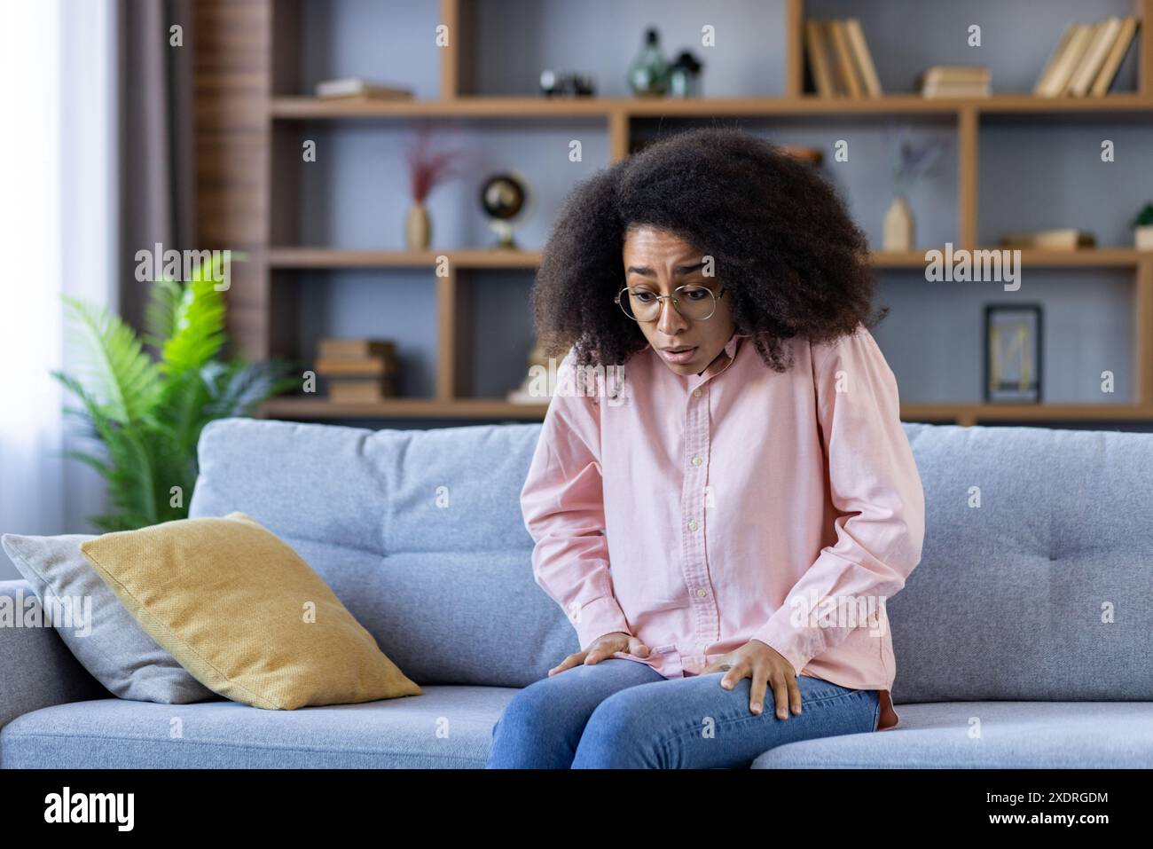 Woman on couch appearing anxious and distressed, likely experiencing ...