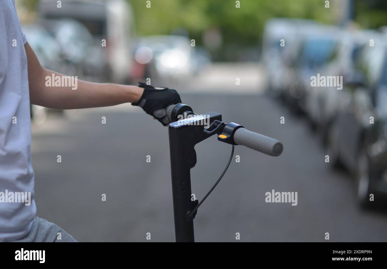 A man with an electric scooter. Close up photo of hands in sport gloves ...