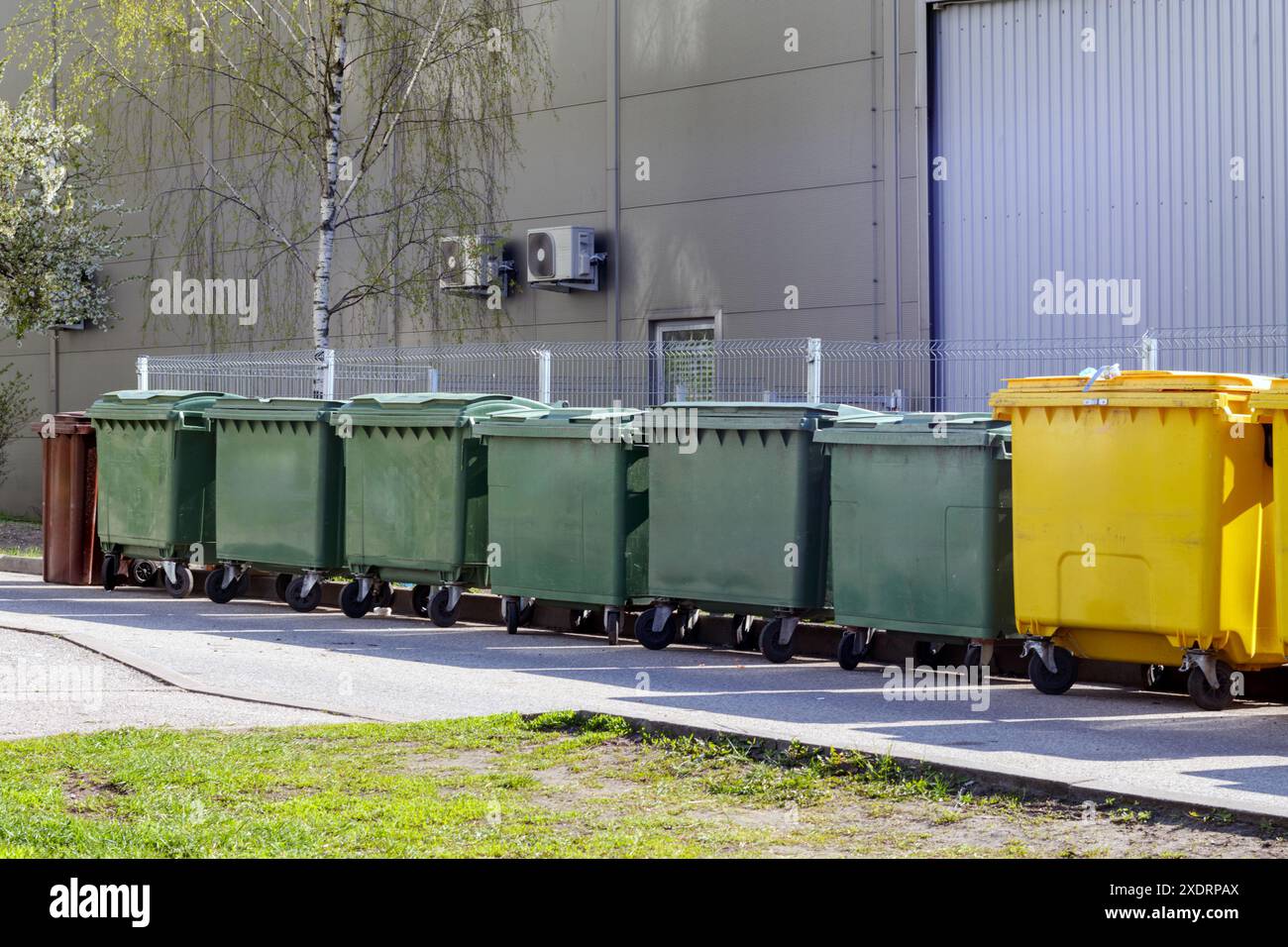 garbage containers on the wall of a gray building Stock Photo - Alamy