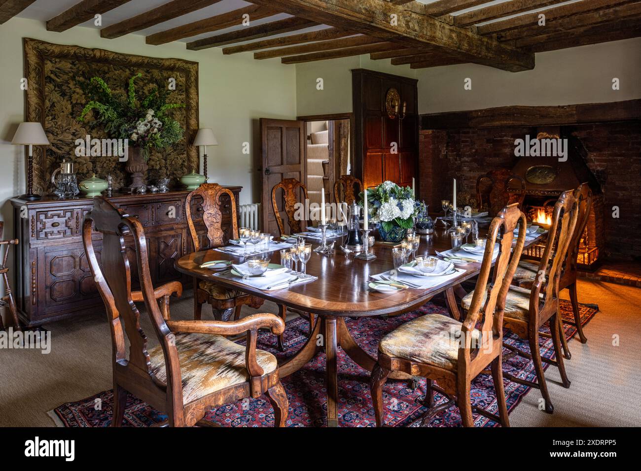 Beamed dining room with lit fire and tapestry with antique marquetry ...