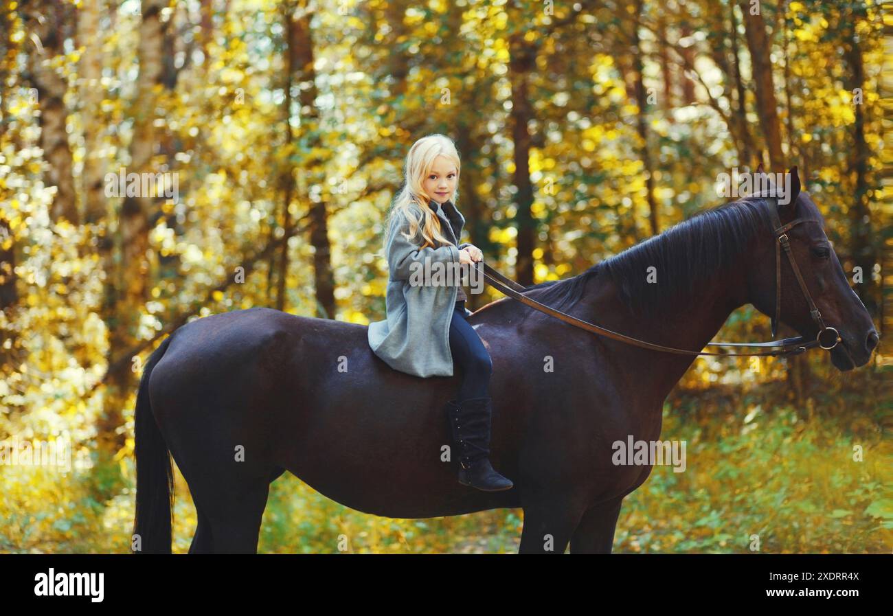 Teenager girl kid sitting on a horse walking in summer forest ...