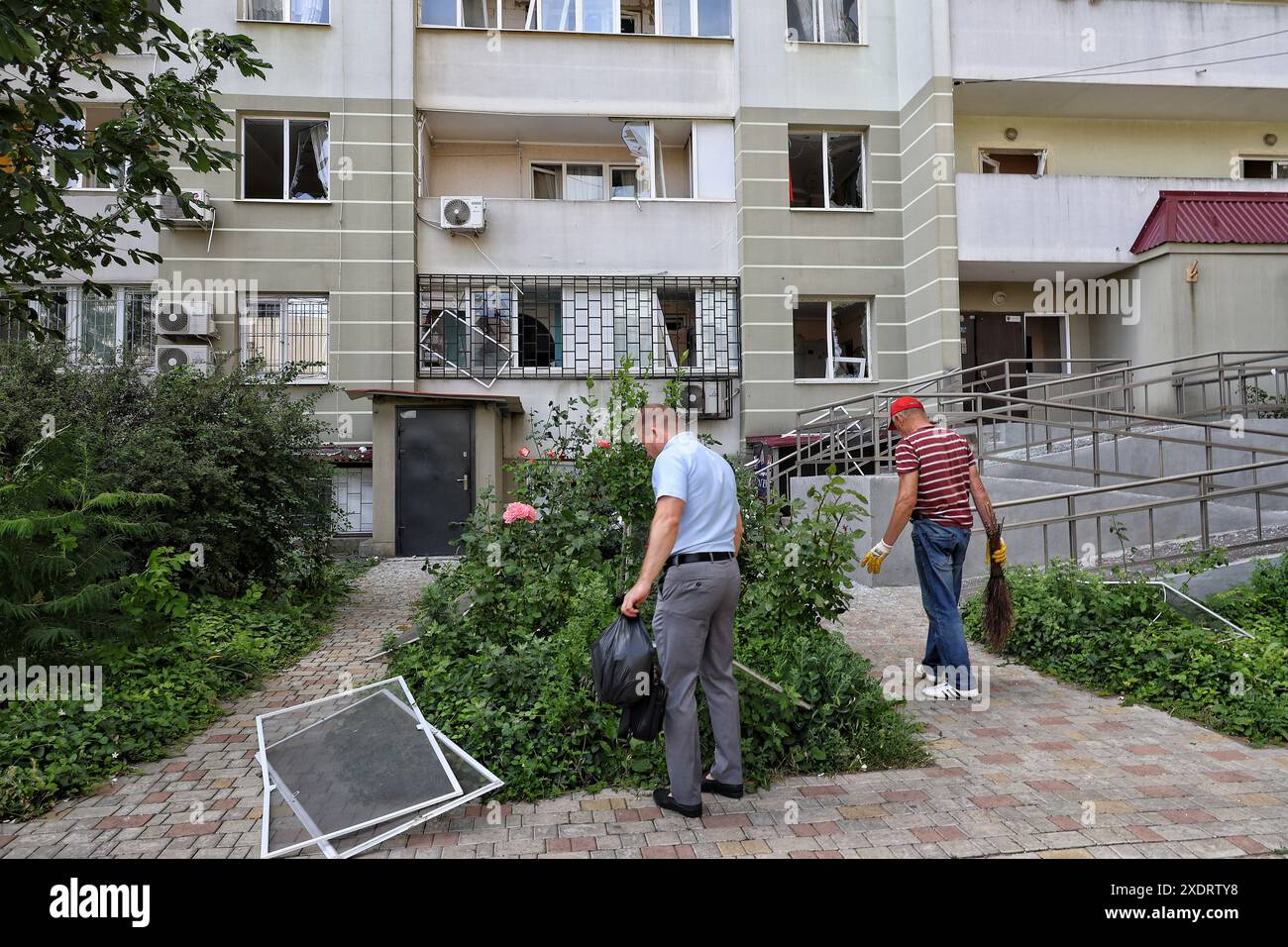 ODESA, UKRAINE - JUNE 24, 2024 - Men clean the territory outside an ...