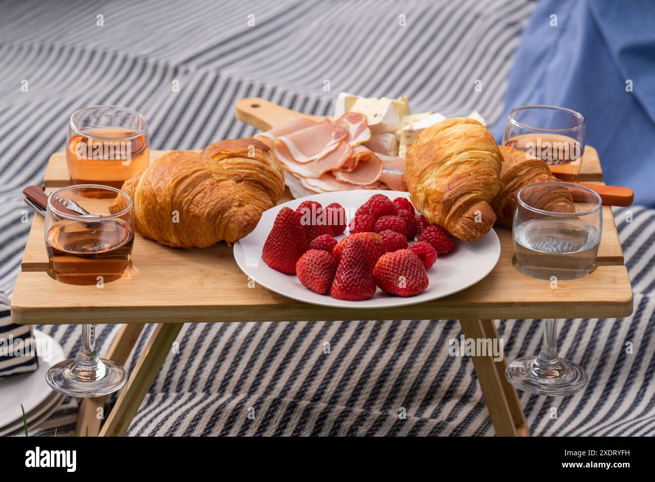 A small table served with picnic food stands on a green clearing in a ...