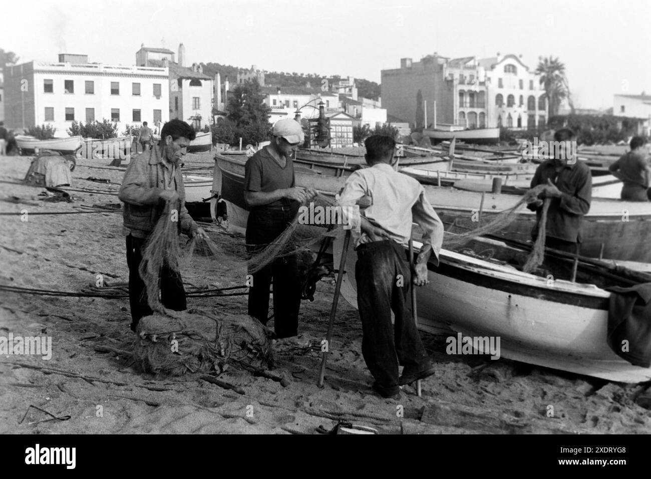 Männer entwirren ein Fischernetz am Starnd von Tossa de Mar, Katalonien ...