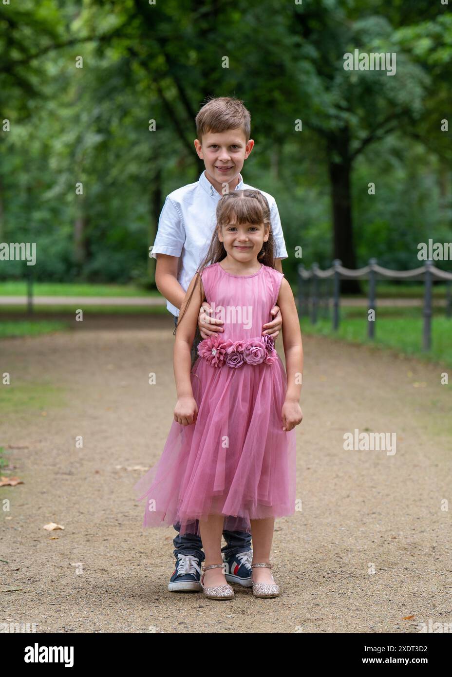 Portrait of brother and sister. A 10-year-old boy hugs his 6-year-old ...