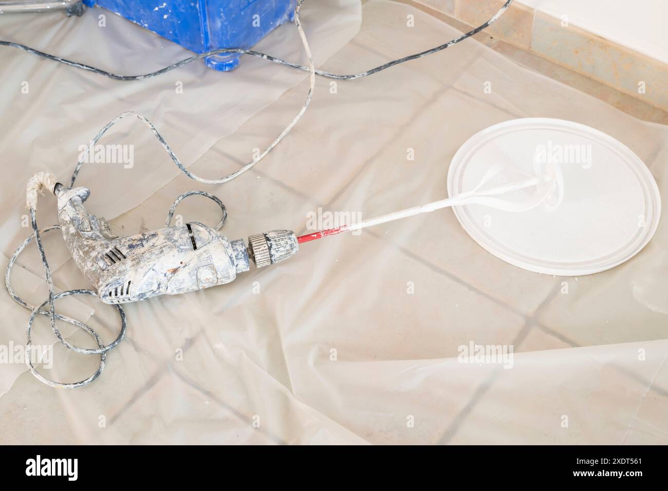 A paint mixer covered with white paint lies on the ground outside a ...