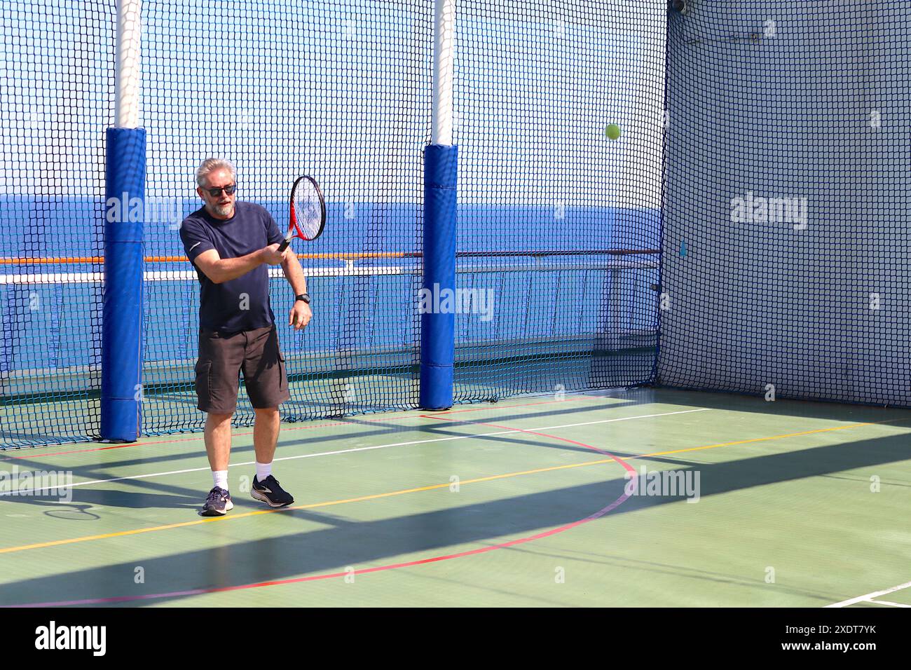 A male cruise guest enjoys a game of tennis in an onboard games area ...