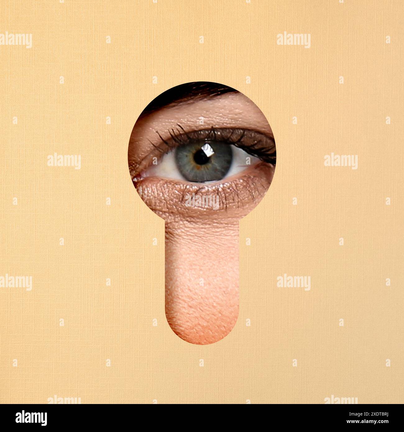Woman looking through keyhole in beige surface Stock Photo - Alamy