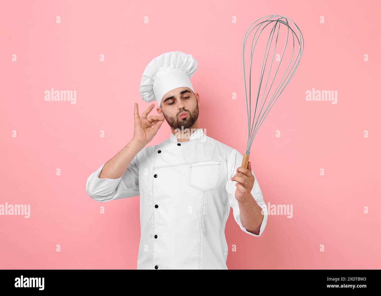 Happy pastry chef with big whisk on pink background Stock Photo - Alamy