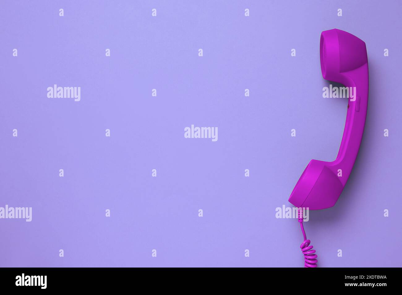 Purple telephone handset on violet background, top view. Space for text ...
