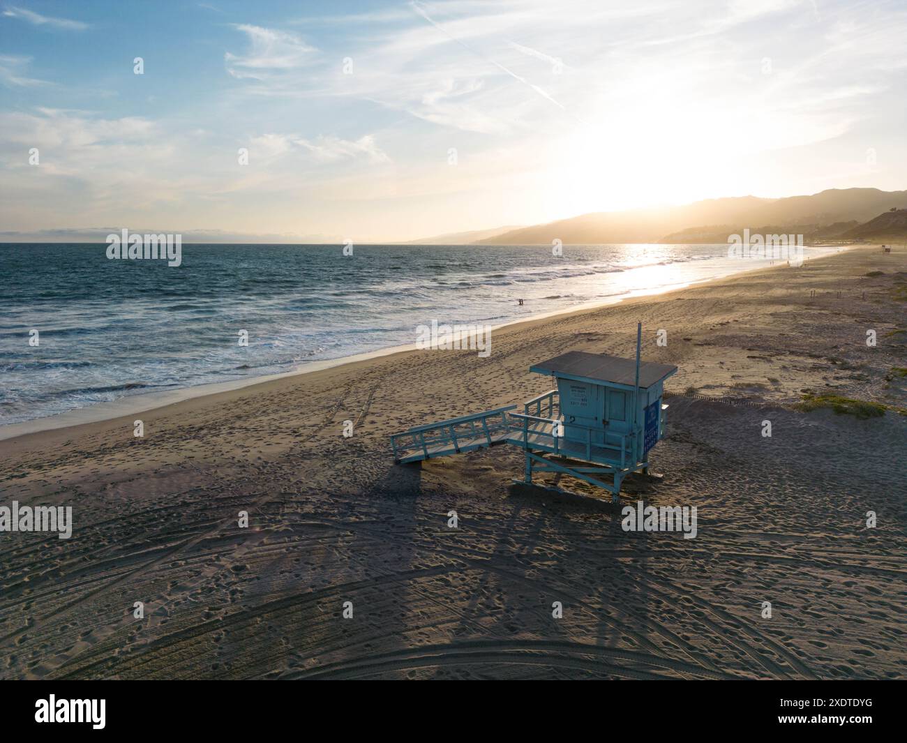 A serene beach landscape with a lifeguard tower at sunset, showcasing ...