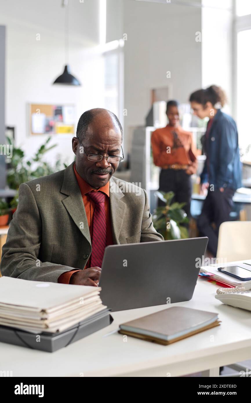 Vertical portrait of African American senior man using laptop at age ...