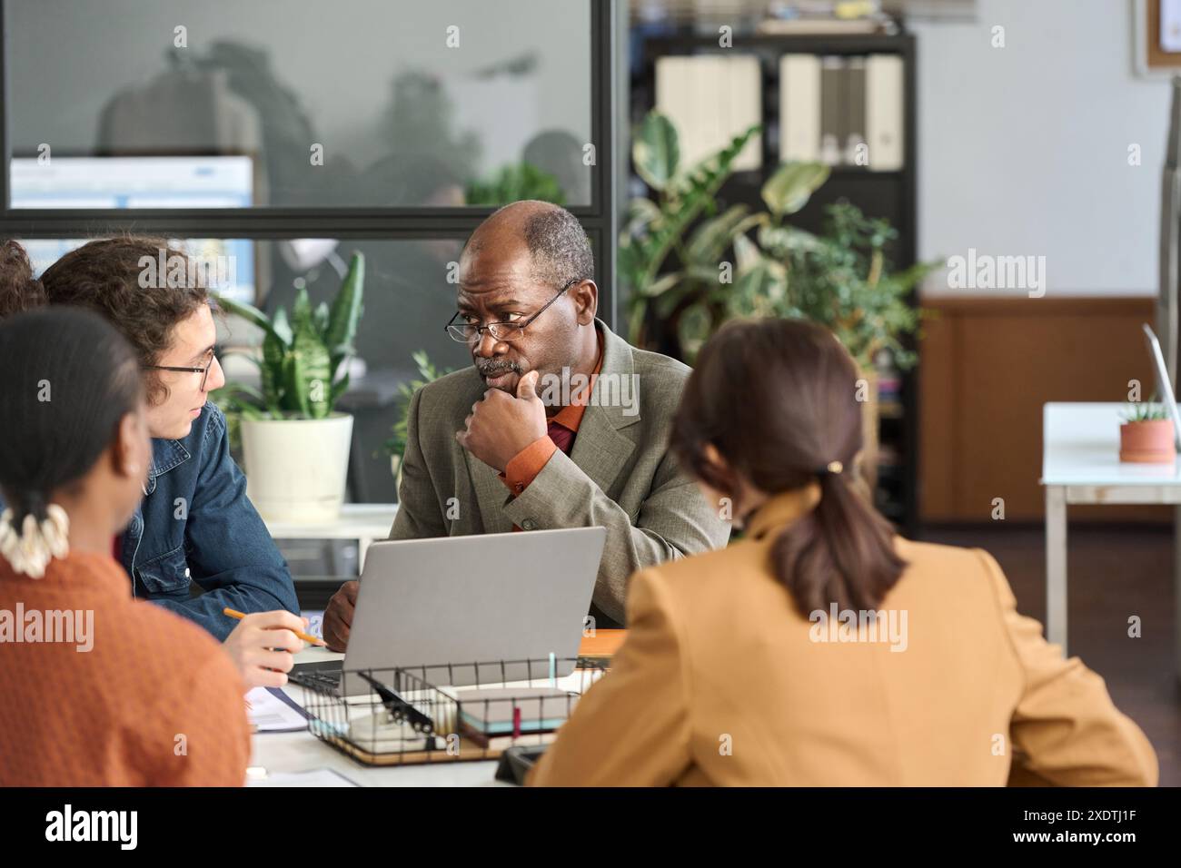 Diverse group of business people sitting at meeting table together and ...