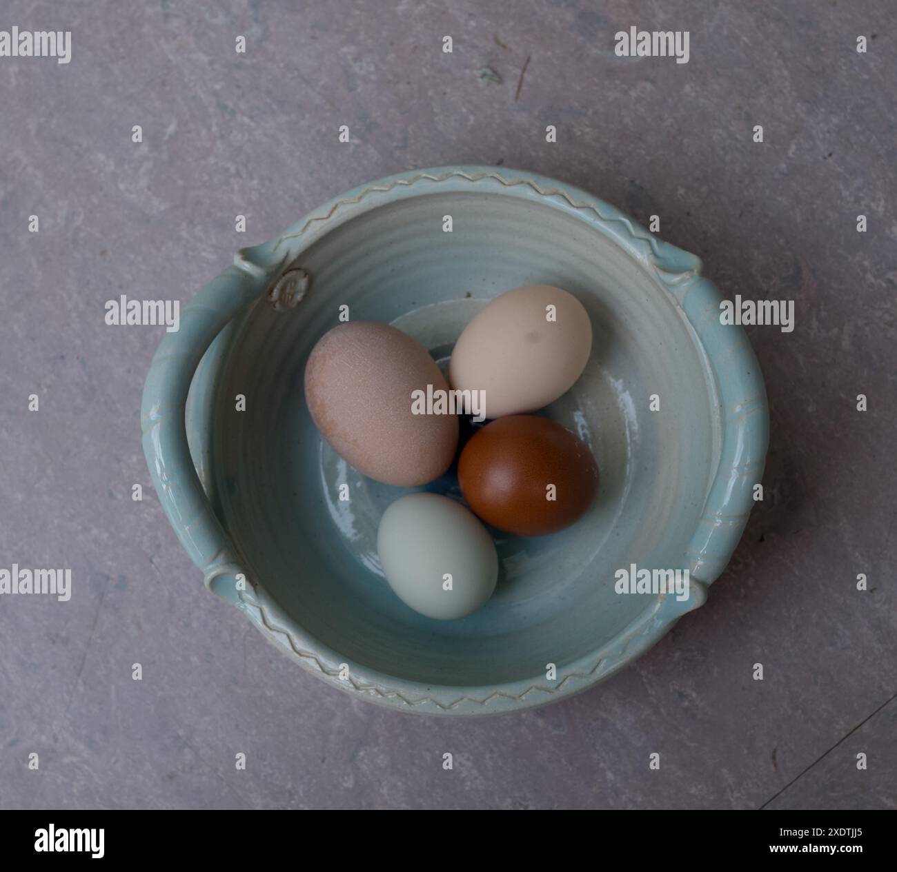 4 hens eggs in a blue ceramic bowl with handles Stock Photo - Alamy