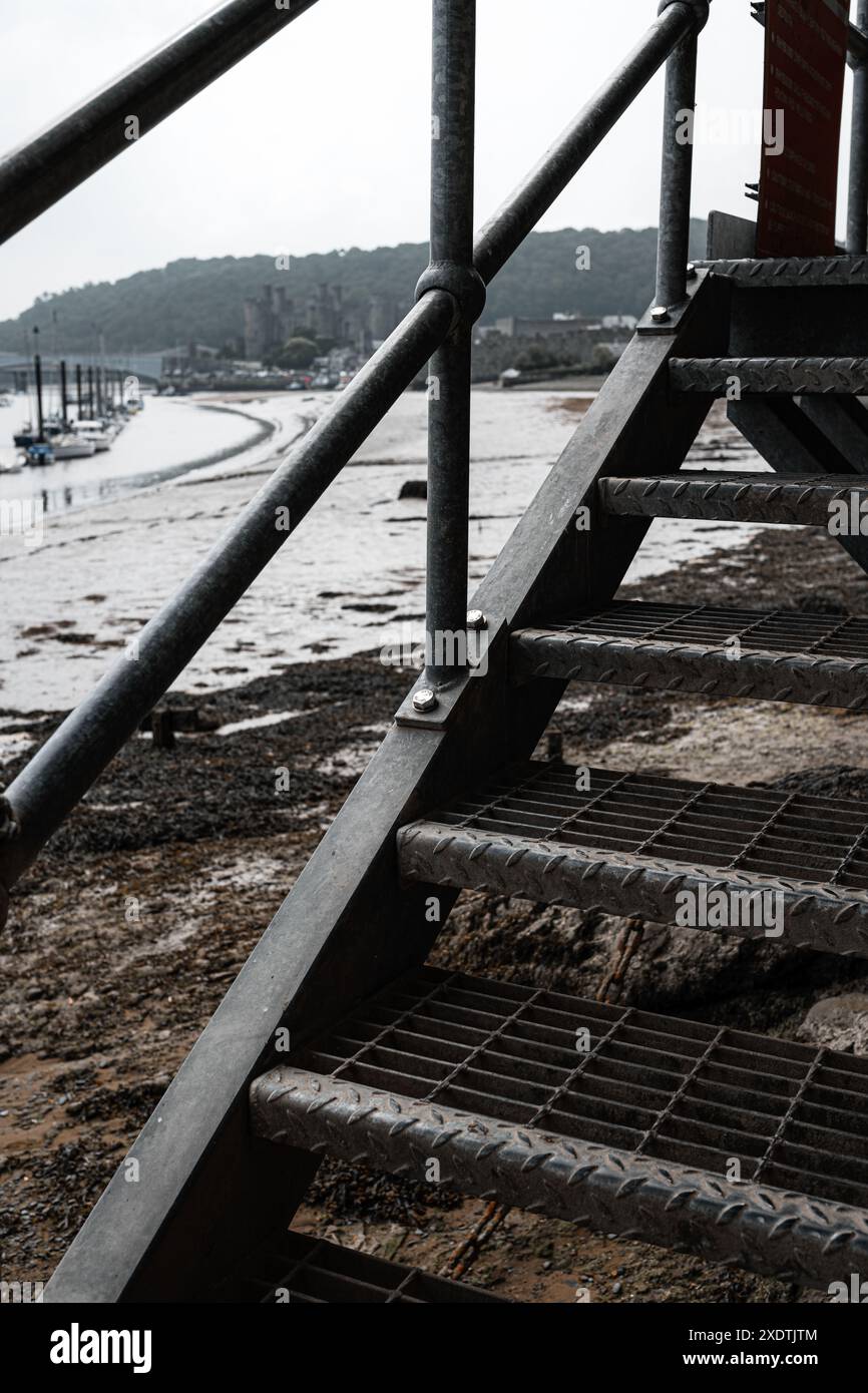 A vertical shot of steel stairs leading down to a serene riverside with ...
