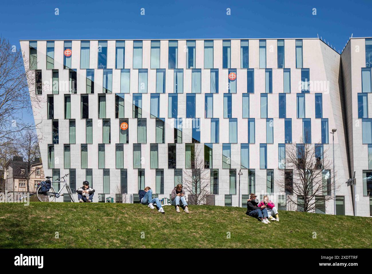 People sitting on a grassy knoll in Dallapé Park with OP Group ...