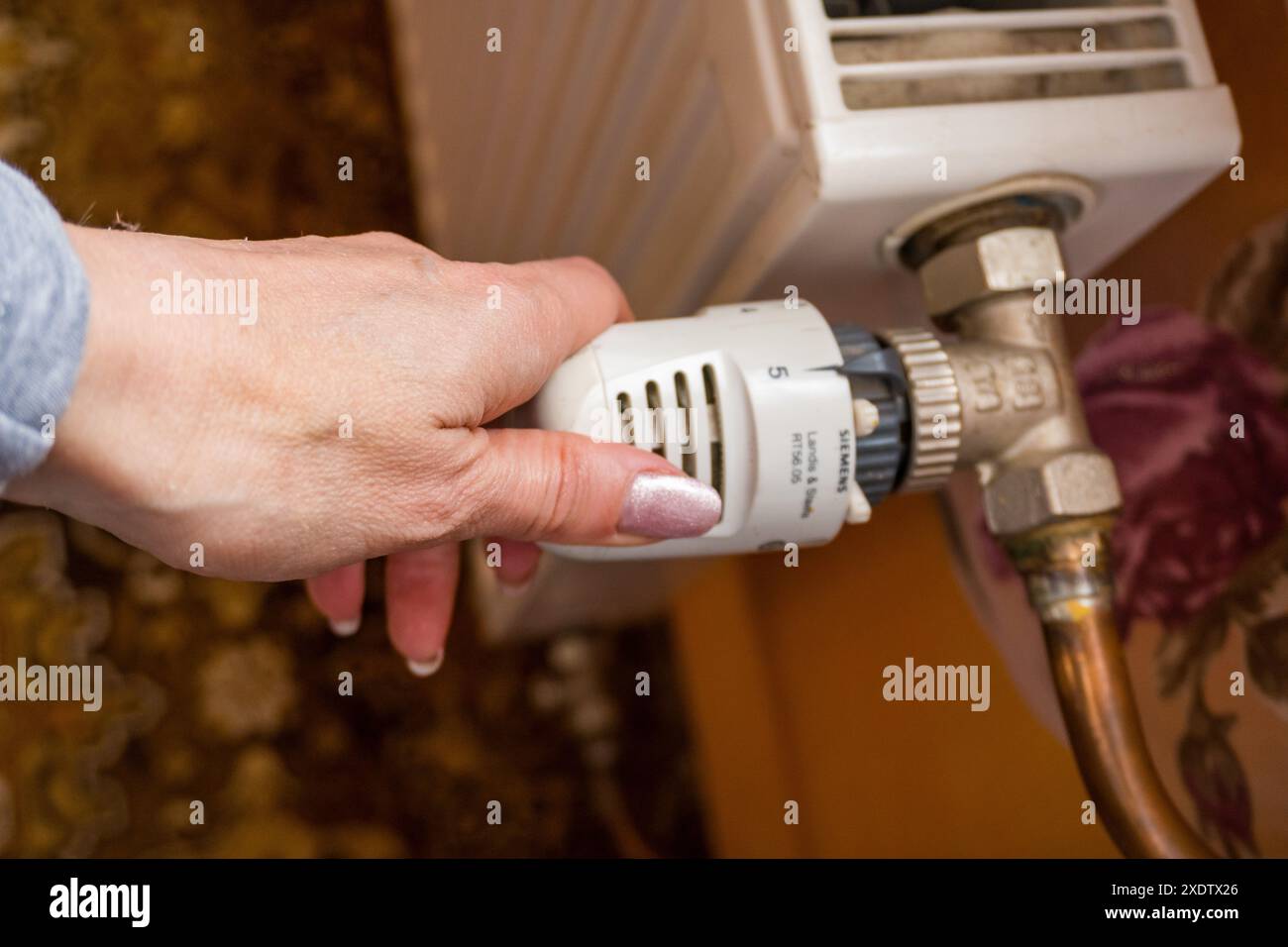 Hand adjusting temperature on heating radiator thermostat, Economy ...