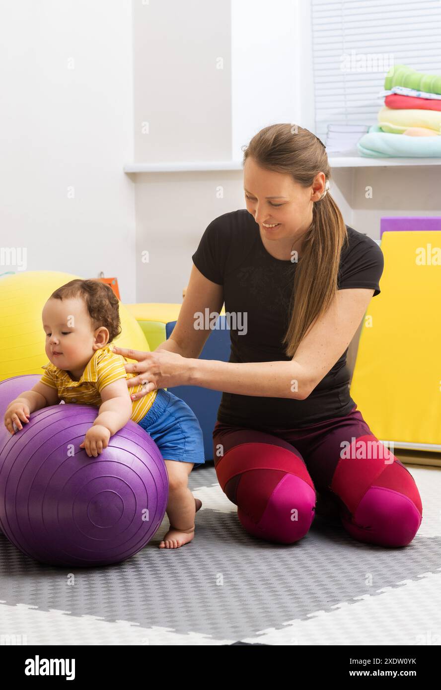 Rehab specialist sitting on purple exercise ball while holding baby ...
