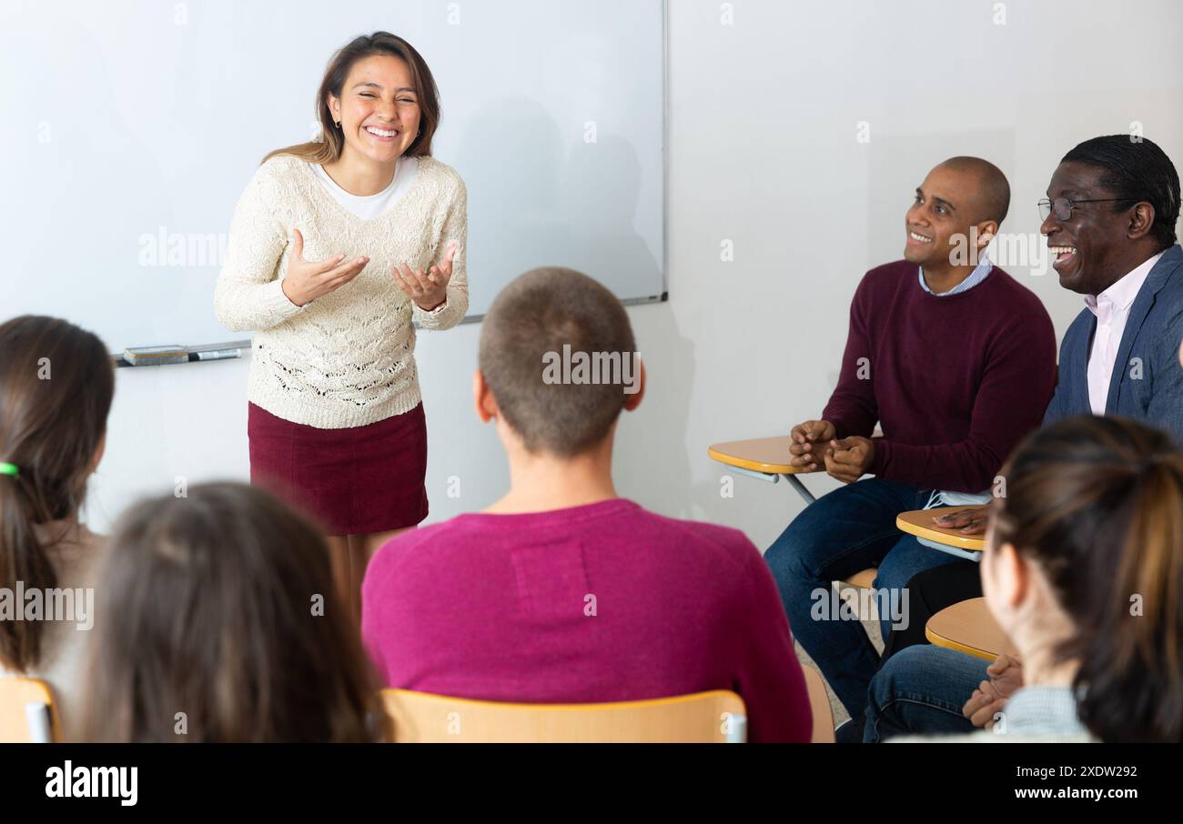 Latina teacher standing in front of whiteboard and teaching lesson ...