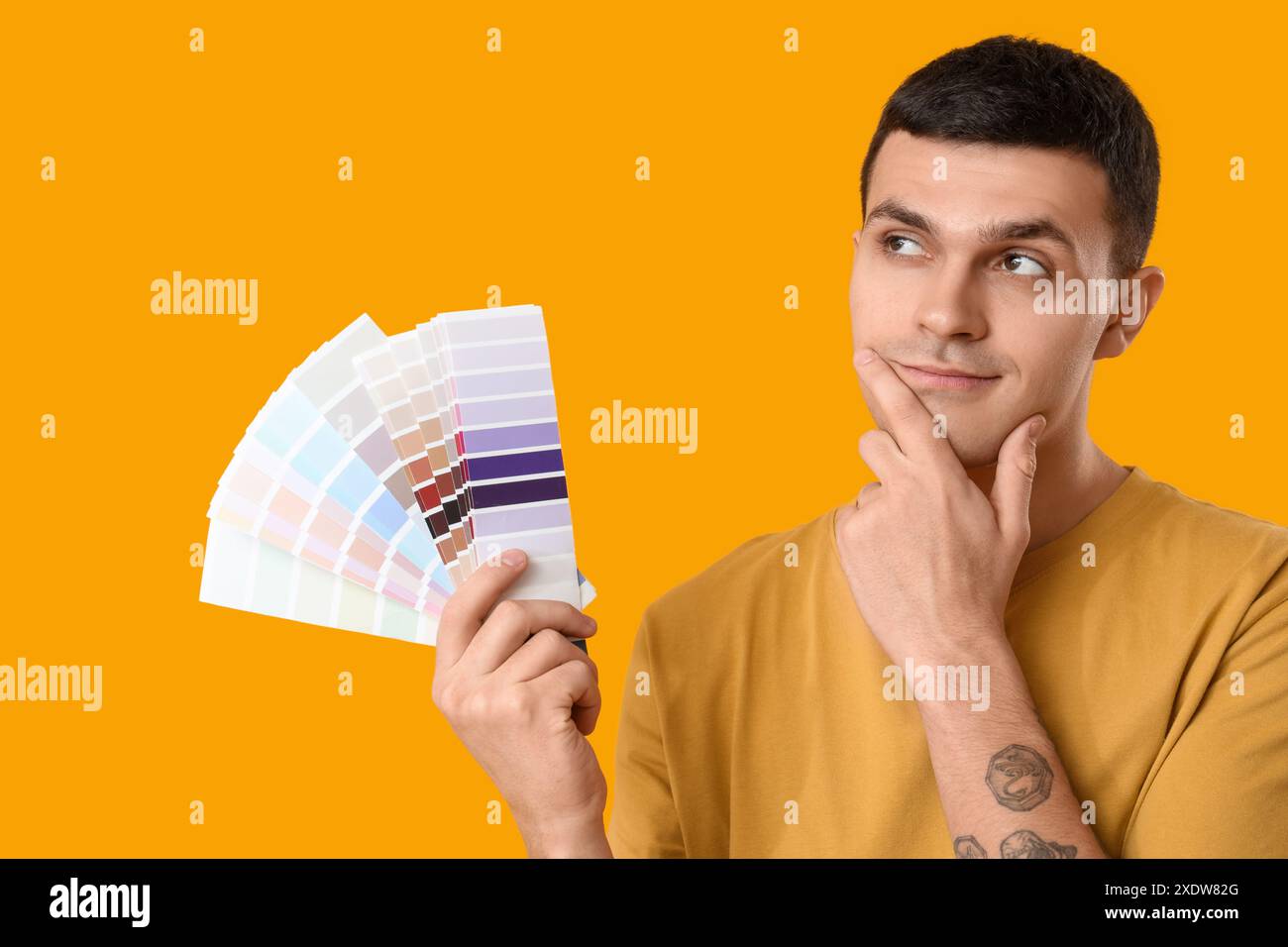 Young man with paint palettes on yellow background Stock Photo - Alamy
