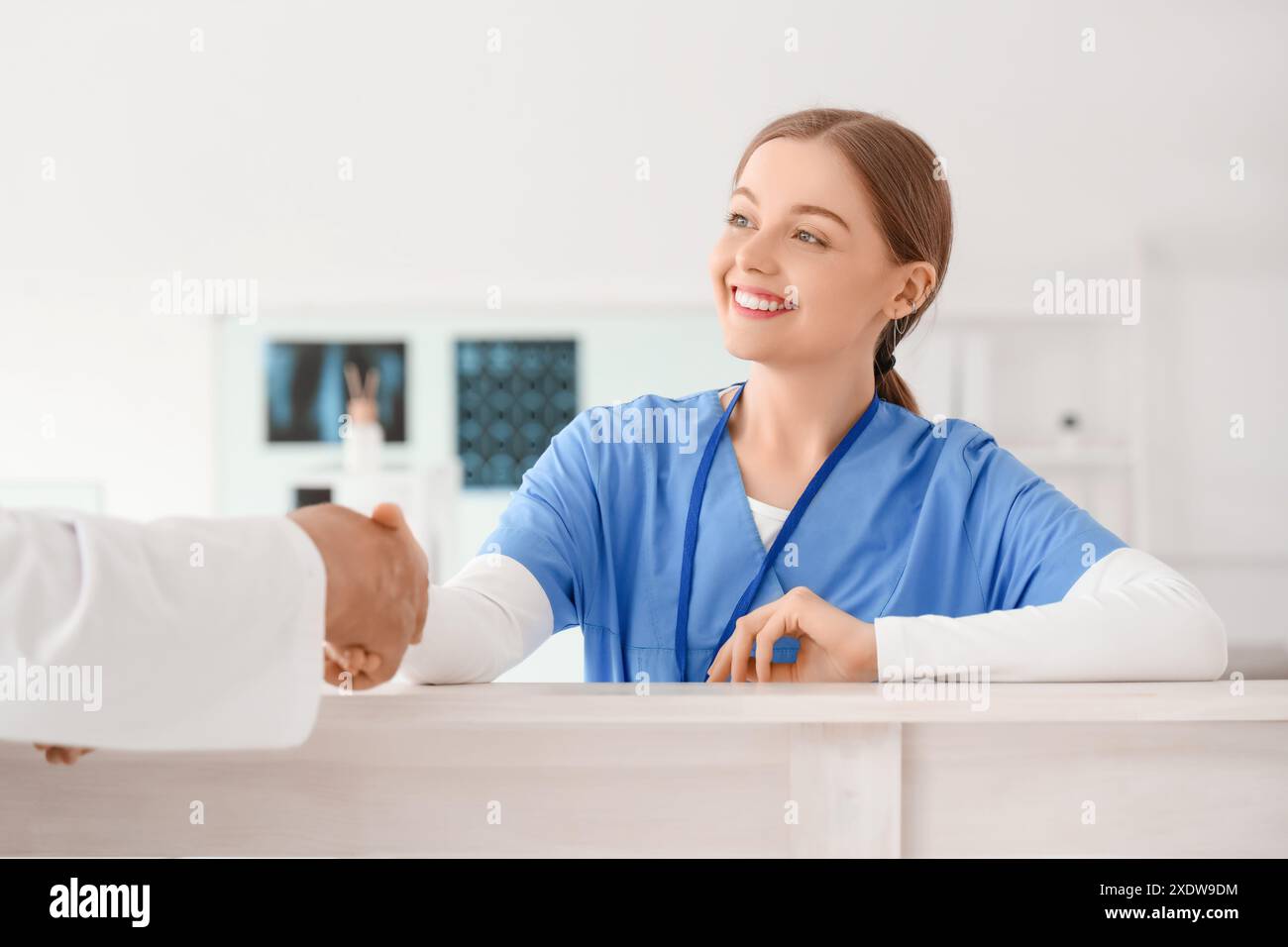 Female nurse with doctor shaking hands at reception in clinic Stock ...