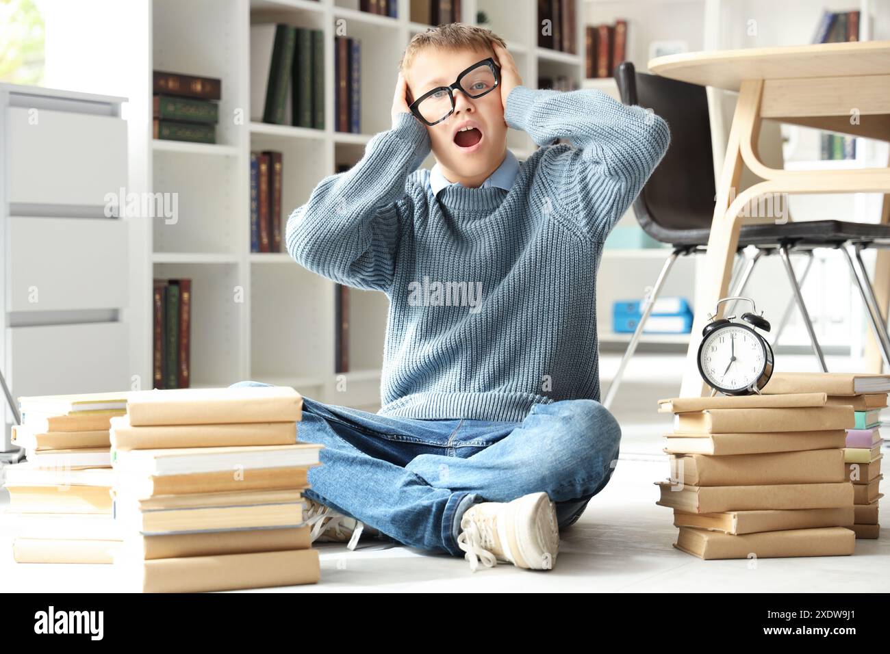 Stressed teenage boy with books sitting in library Stock Photo - Alamy