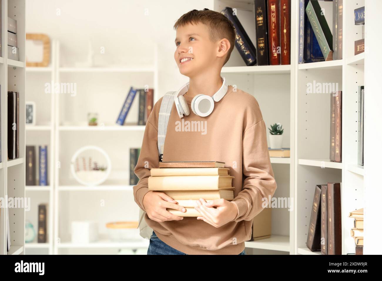 Teenage boy with backpack and books in library Stock Photo - Alamy