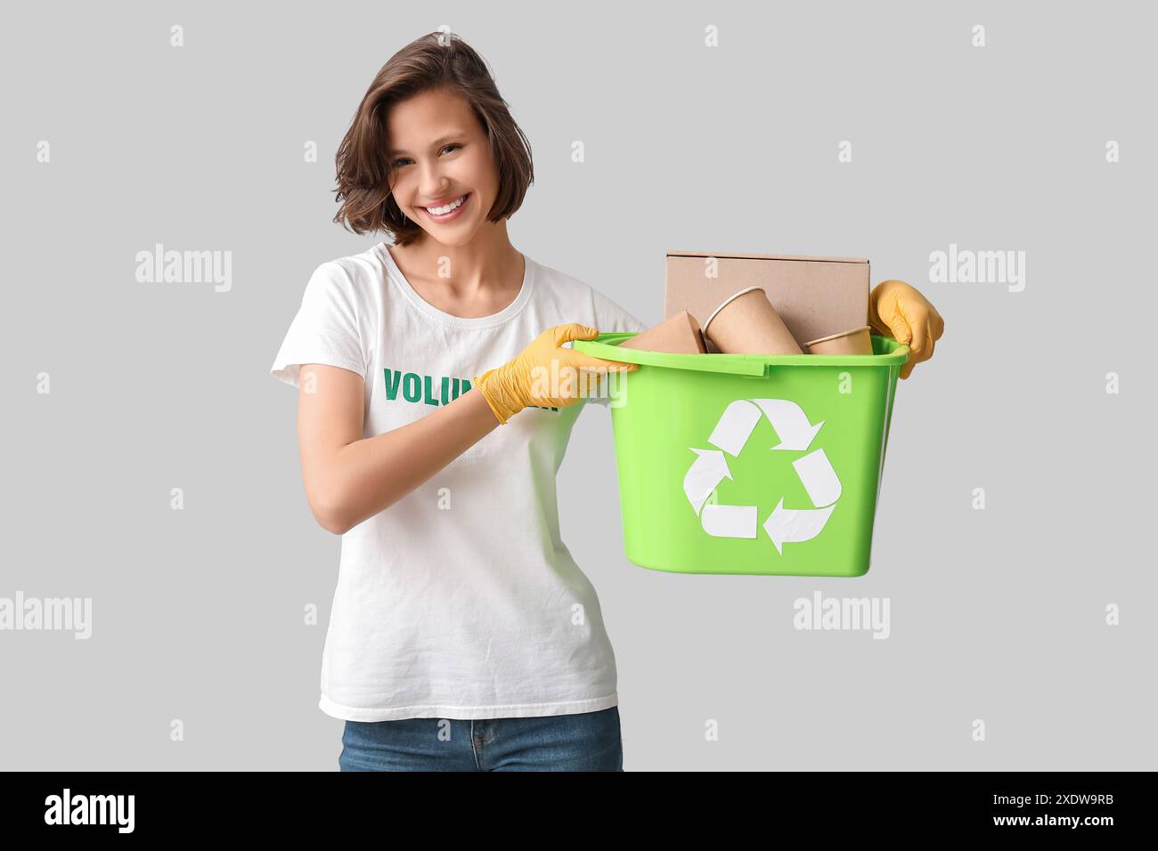Female volunteer holding recycle bin with garbage on white background ...