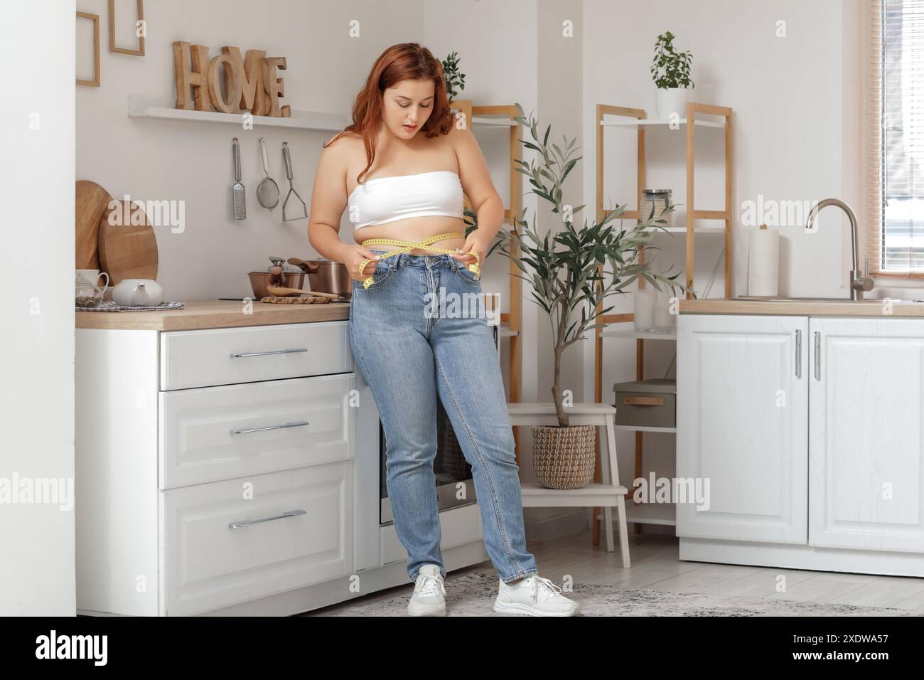Overweight young woman with measuring tape in kitchen at home. Weight ...