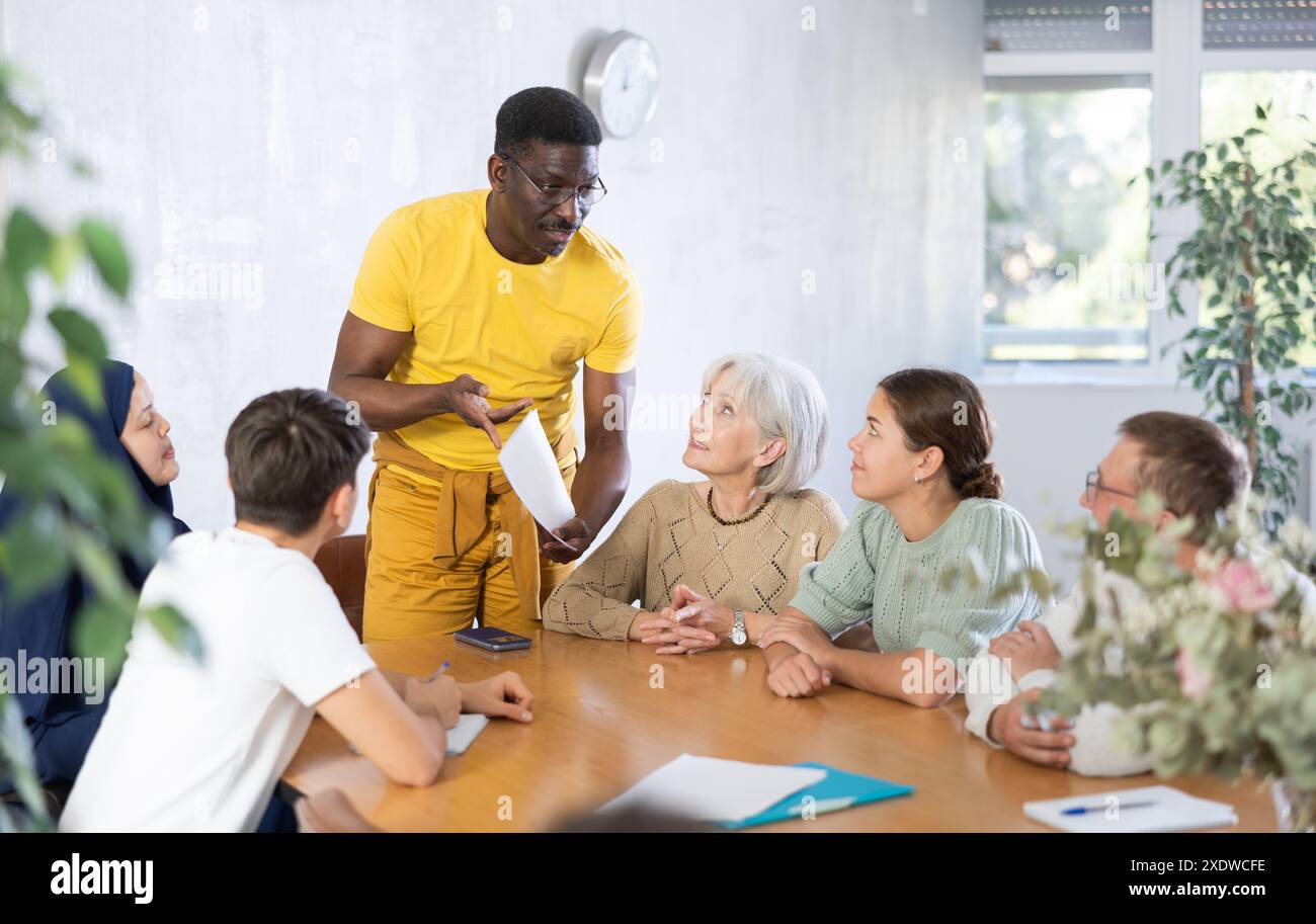 African American tutor conducting lesson for group of adult people ...
