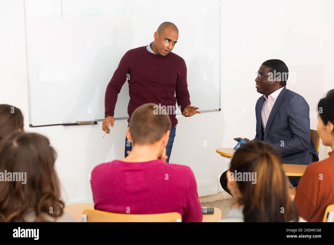 Hispanic lecturer is pointing something on board to his students Stock ...