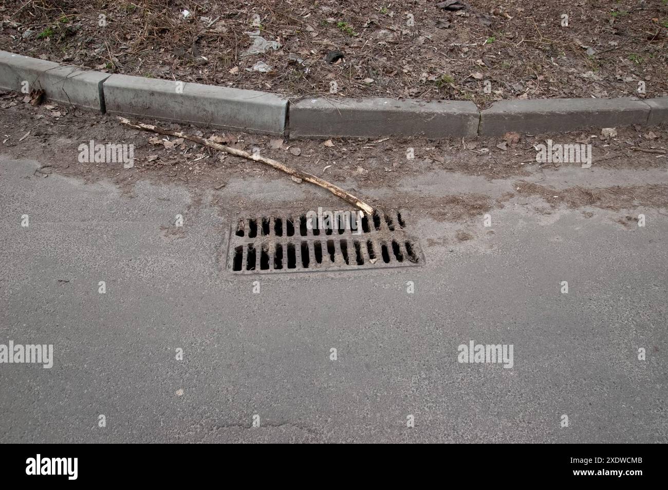 a rusty, dirty storm drain grate in the middle of an asphalt road Stock ...