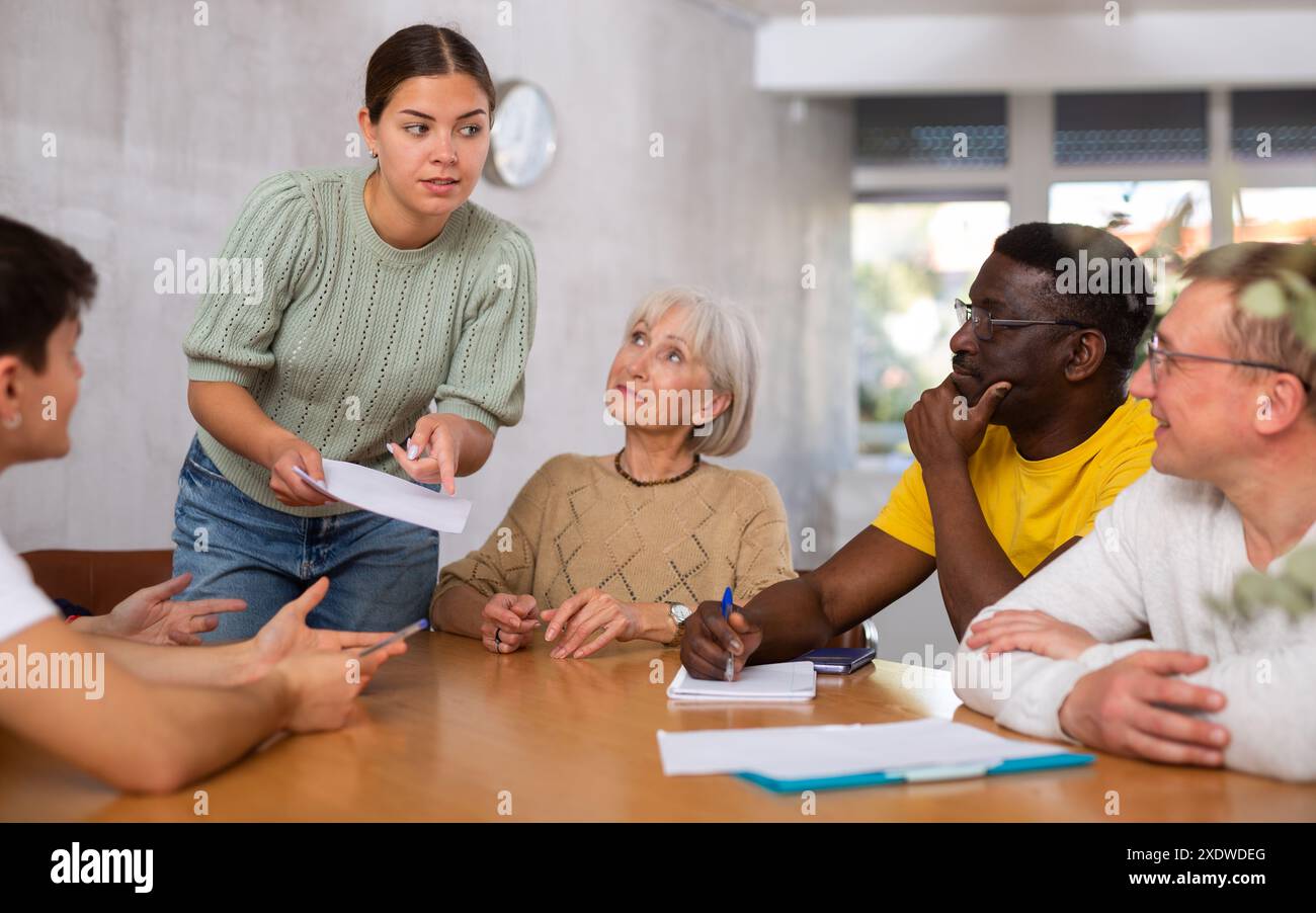 Cheerful girl student talking with friendly coursemates in classroom ...