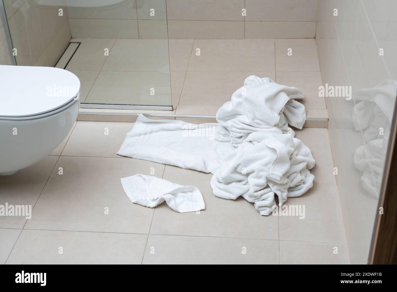 Pile of dirty used towels on the floor in hotel bathroom. Housekeeping ...