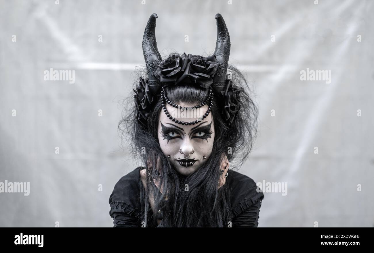 woman in gothic attire stares intensely at camera. wears black horns ...
