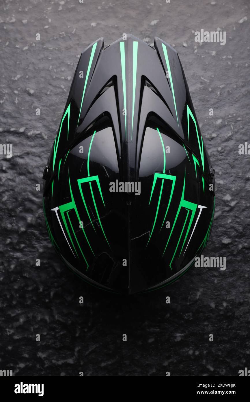 Modern motorcycle helmet with visor on black stone surface, top view ...