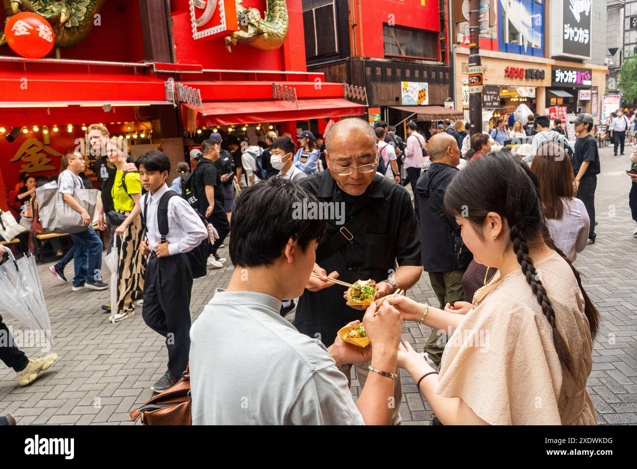 Osaka Japan people eating street food Stock Photo - Alamy