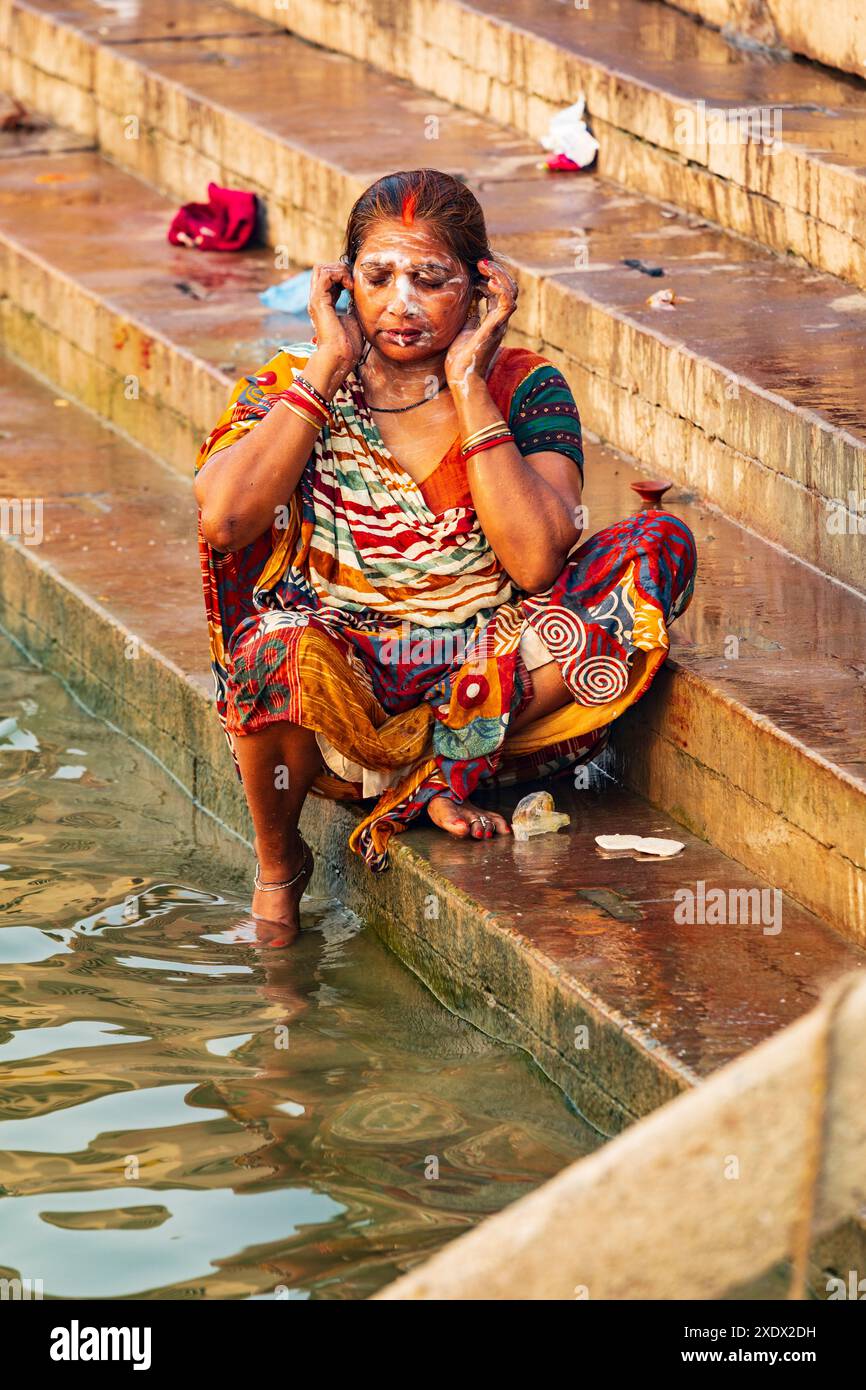 India, Uttar Pradesh, Varanasi. A woman in a colorful sari on the steps ...