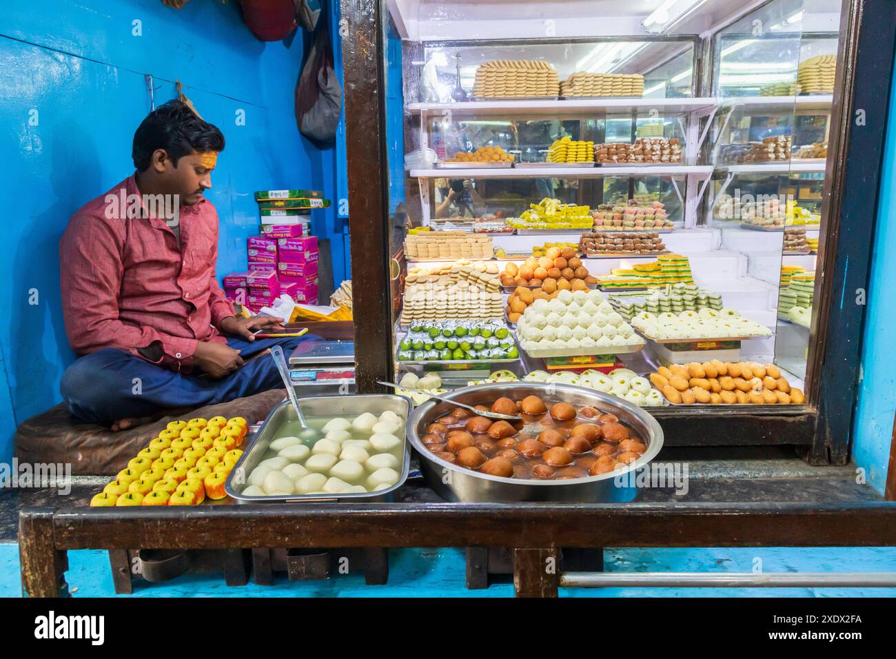 India, Uttar Pradesh, Varanasi. A food vendor making and selling sweet ...