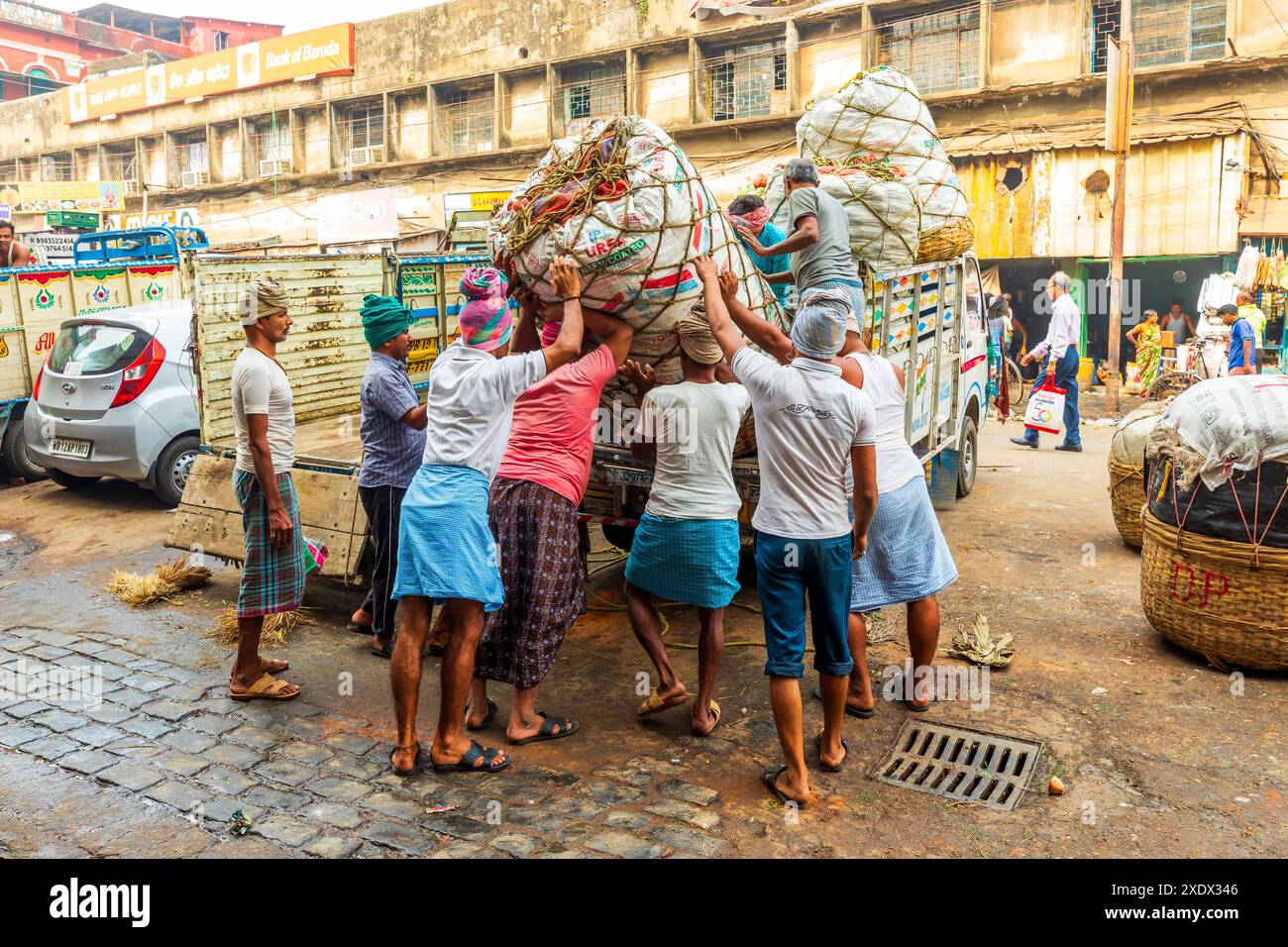 India, West Bengal, Kolkata, Bow Bazaar. Men working together to lift a ...