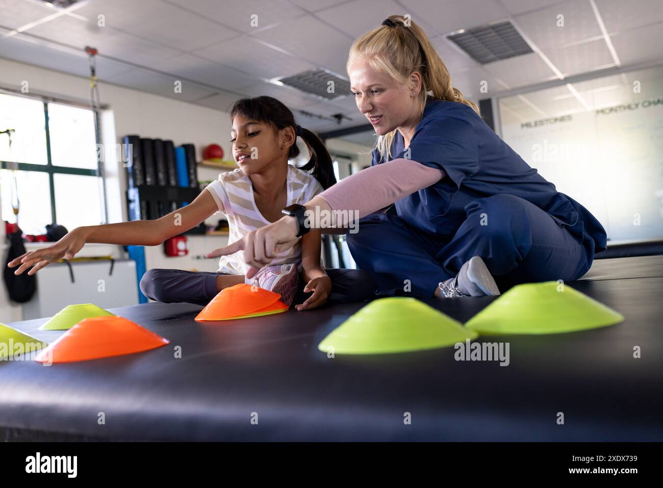 Female therapist guiding girl with cerebral palsy in physical rehab ...