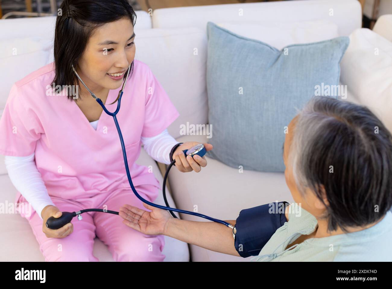 Female nurse checking blood pressure of senior patient at home, smiling ...