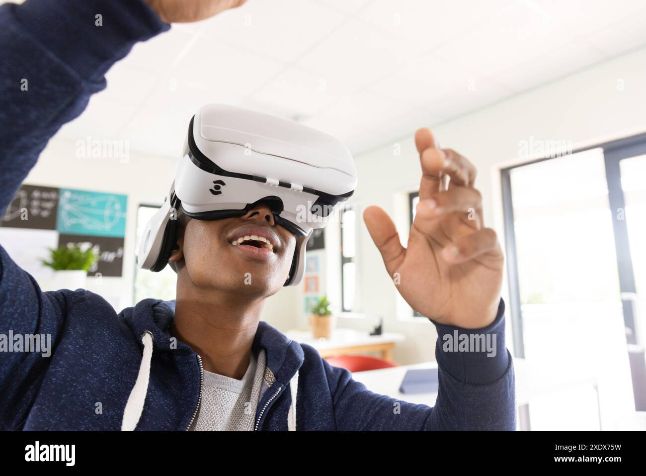 Using VR headset, African American male student experiencing virtual ...