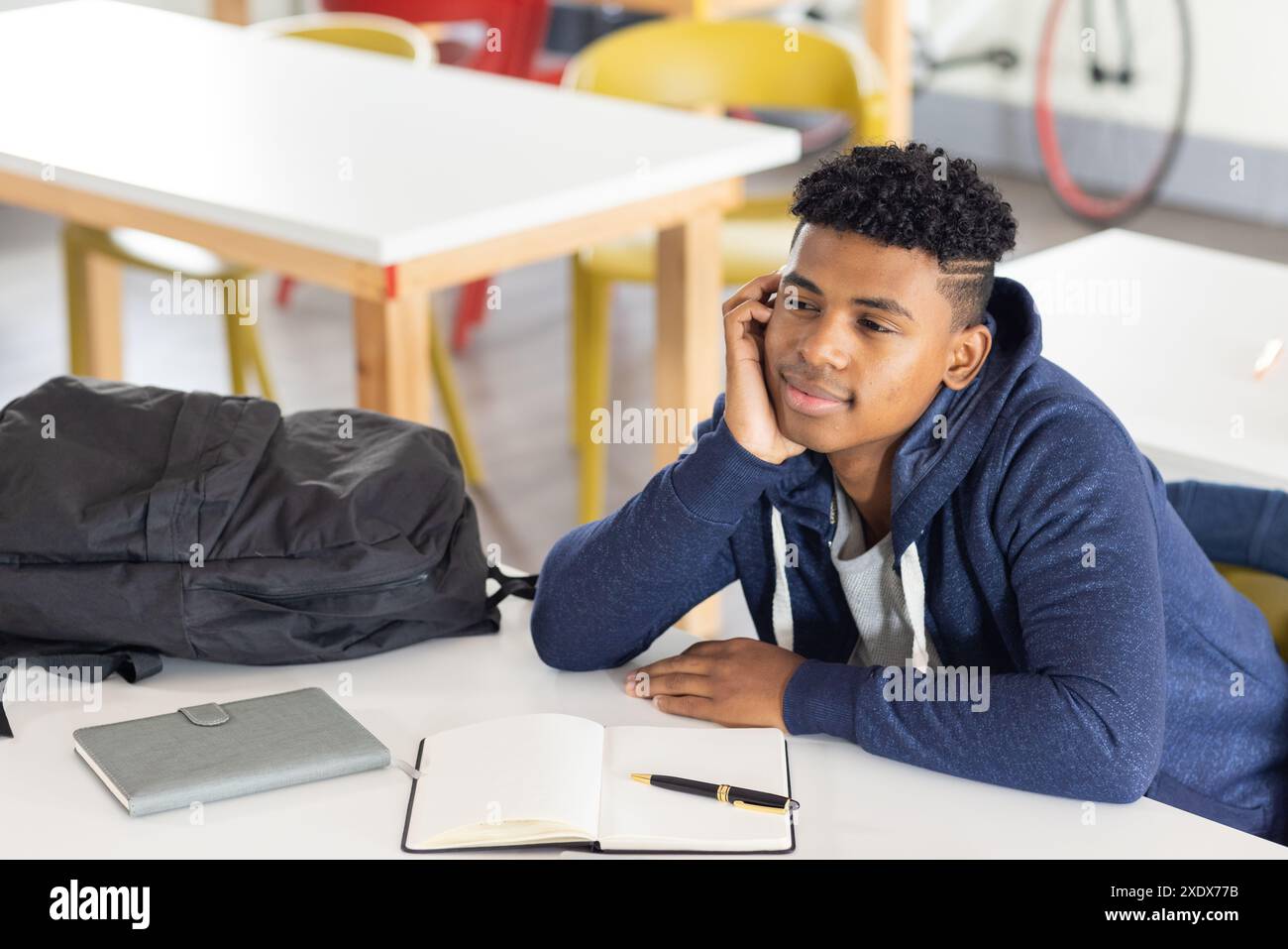 In school, African American male student daydreaming at desk with ...