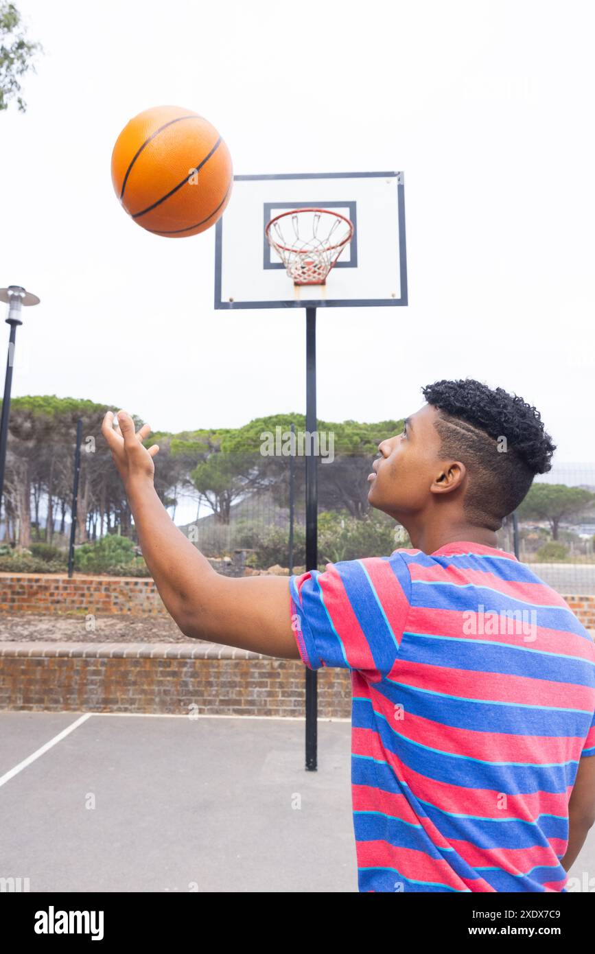 Playing basketball outdoors, teenage boy spinning ball on finger near ...