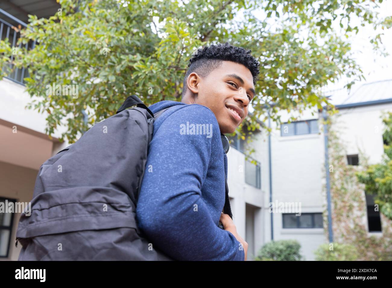 Carrying backpack and smiling, African American male student looking ...
