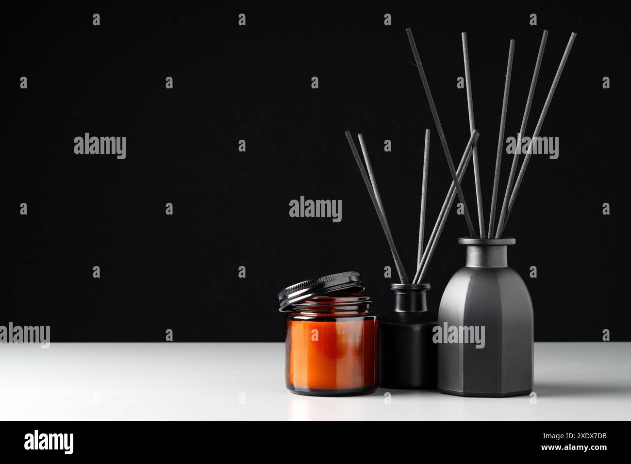 Black Reed Diffuser and Candle on Grey Surface Against Black Background ...