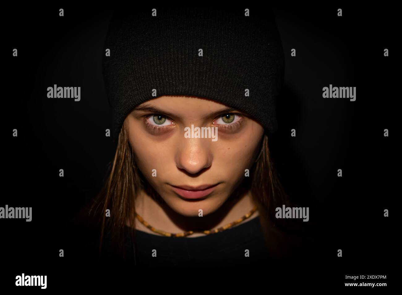 Close-up portrait of a teenage girl wearing a black cap, looking ...