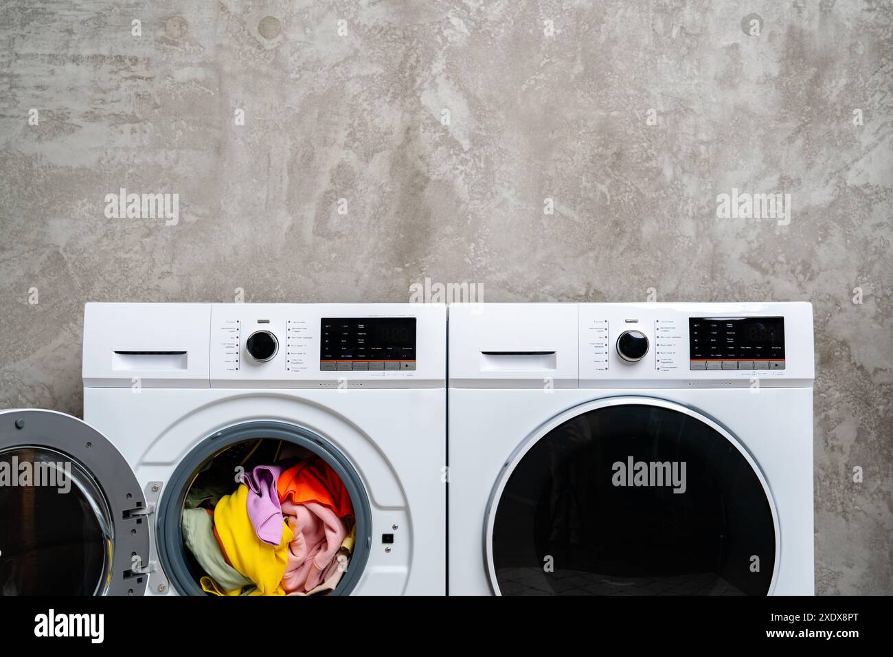 White Laundry Machines Against a Grey Concrete Wall Stock Photo - Alamy