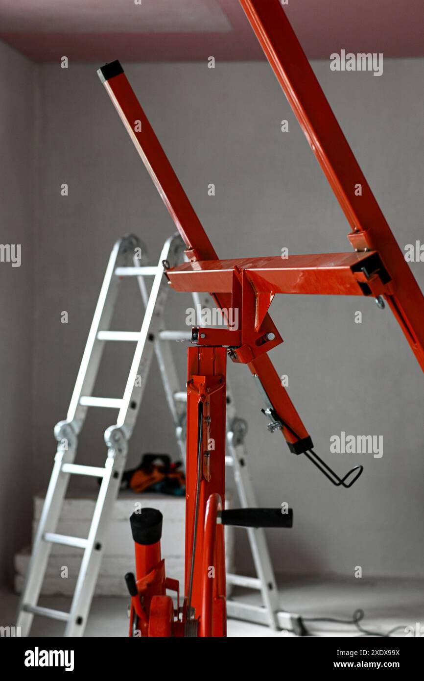 Red metal lifting platform standing on concrete floor inside unfinished ...